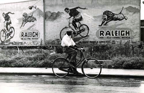 Man riding bike while passing a bike ad